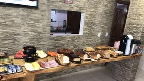 Uma mesa de buffet com diversos alimentos e um espaço para café.