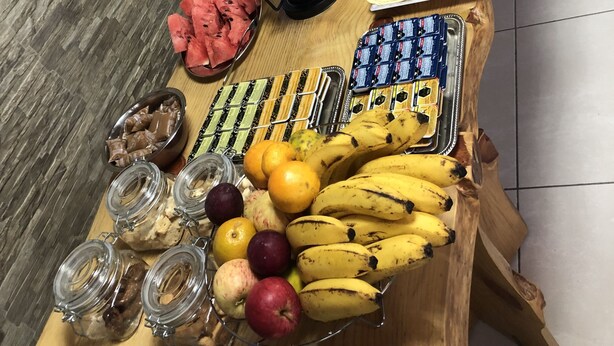 Mesa de buffet com diversas opções de comida, incluindo frutas, doces e acompanhamentos.