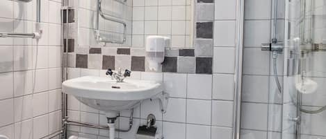 Casa de banho moderna com lavatório branco, espelho e cabine de duche em vidro.