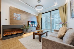Uma sala de estar moderna com lareira, sofá, mesa de centro e uma grande janela com vista para a cidade.