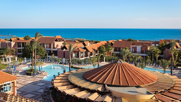 Um resort com piscina, espreguiçadeiras e vista para o mar.