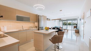 Uma cozinha moderna com uma ilha central, um espaço de refeições com balcão e vista para o exterior.