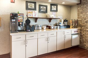 Uma cozinha compacta equipada com cafeteira, máquina de waffles e geladeira.