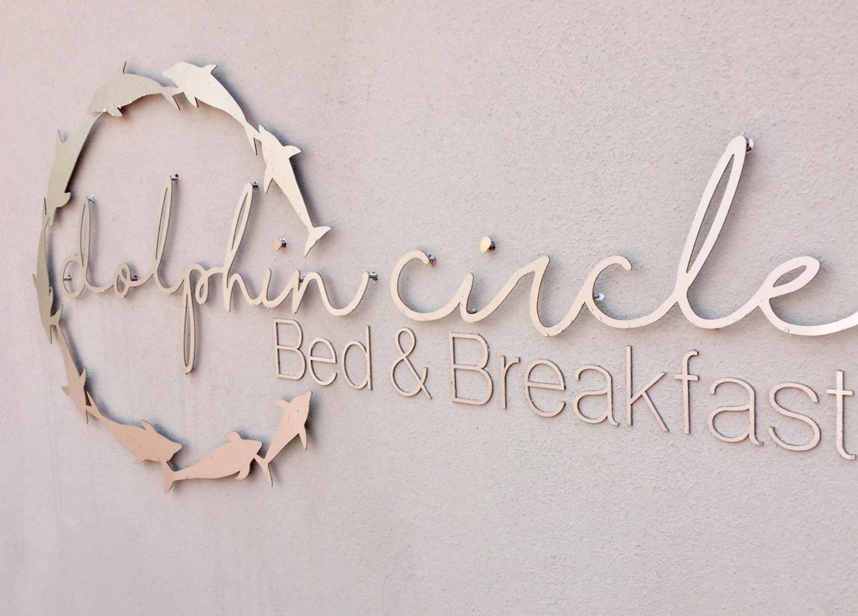 Placa na parede para 'Dolphin Circle Bed & Breakfast', com design de desenho de golfinho e estrela-do-mar.
