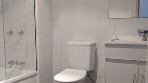Uma casa de banho moderna com sanita, lavatório e chuveiro.