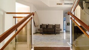 Um interior moderno com escada, sofá e guarda-corrimão de vidro.
