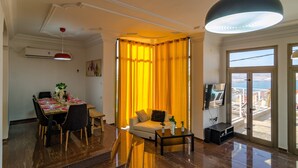 Uma sala de estar moderna com área de jantar, um sofá, uma mesa de centro e uma televisão.