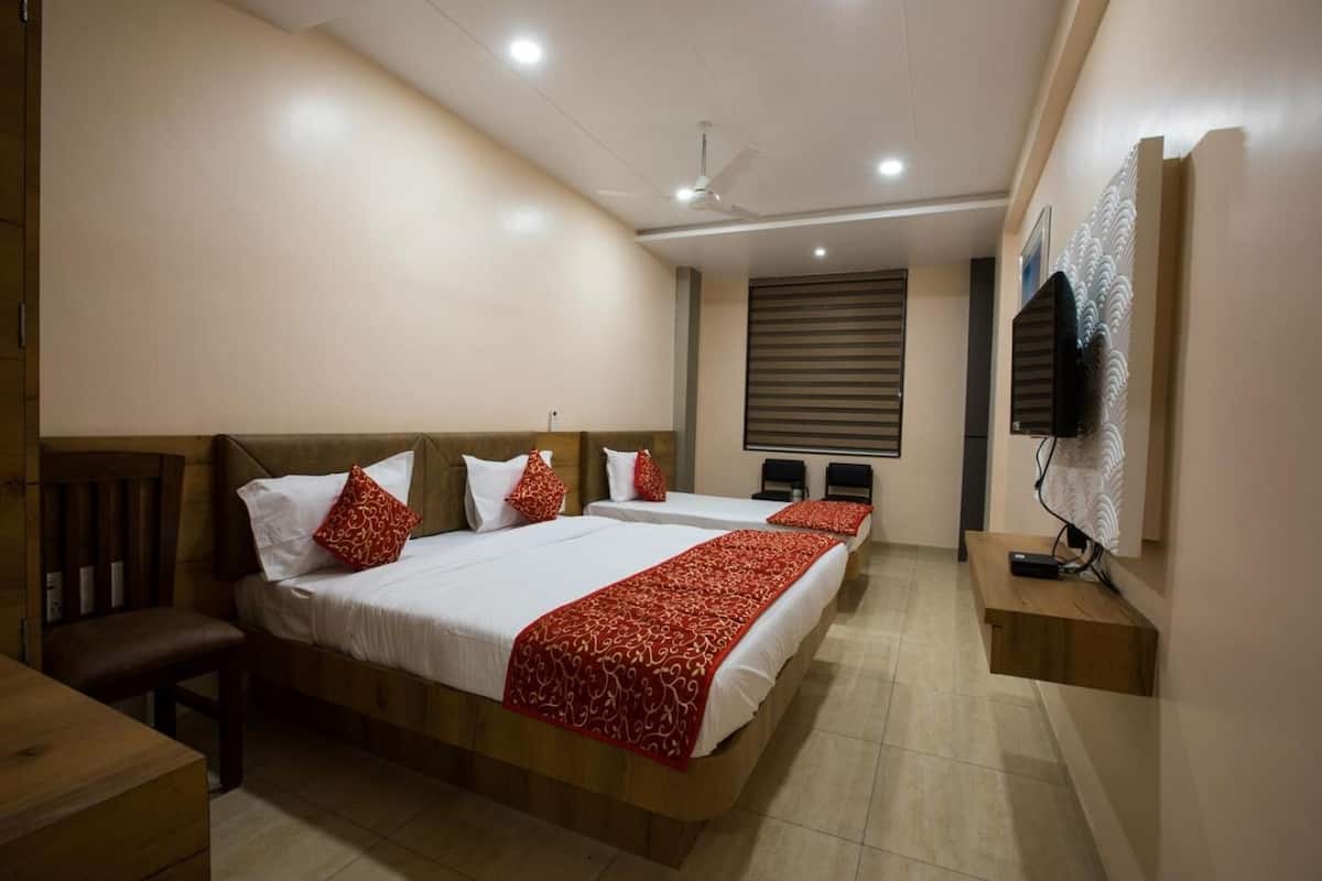 Quarto de hotel com duas camas, um banco de madeira, uma TV e um ventilador de teto.