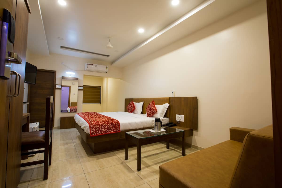 Quarto de hotel com uma cama, uma mesa, uma cadeira, um sofá e uma televisão.