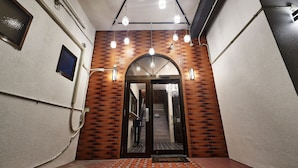 Um corredor com parede de tijolos, porta de vidro e iluminação no teto.