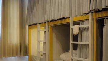 Quarto de hotel com beliches, cortinas e piso ladrilhado.