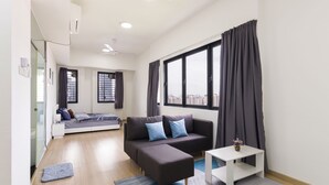 Uma sala de estar moderna com um sofá, uma mesa pequena e vista para a cidade através de grandes janelas.