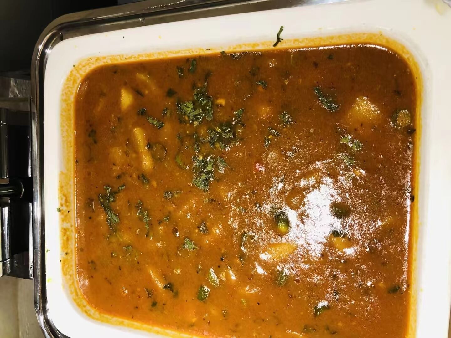 Recipiente retangular cheio de uma sopa espessa, de cor laranja, com ervas visíveis.