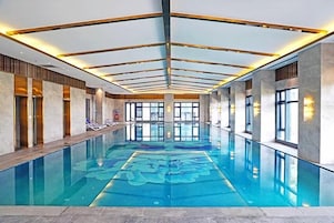 Piscina interna com teto de vidro, várias janelas e vista clara da piscina.