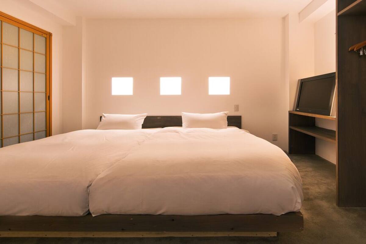 Quarto com uma cama grande, guarda-roupa de madeira, televisão e porta de correr.