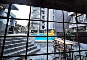 Um edifício moderno com piscina, área de estar externa e vista para um bairro residencial.