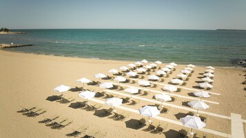 Na praia, espreguiçadeiras, guarda-sóis de praia, massagens na praia 