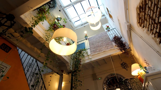 Interior com teto alto, plantas penduradas e uma escadaria.