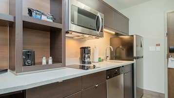 Cozinha moderna com micro-ondas integrado, cafeteira e eletrodomésticos de aço inoxidável.