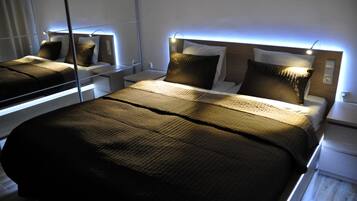 Quarto de hotel moderno com uma cama grande, mesas de cabeceira e um espelho.