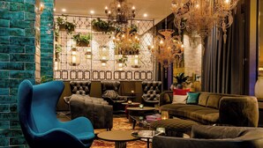 Uma área de estar moderna com assentos confortáveis, iluminação decorativa e painel de parede estampado.