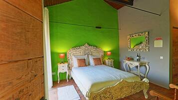 Quarto com uma cama grande, duas mesas de cabeceira com luminárias, um espelho e uma cadeira de madeira.