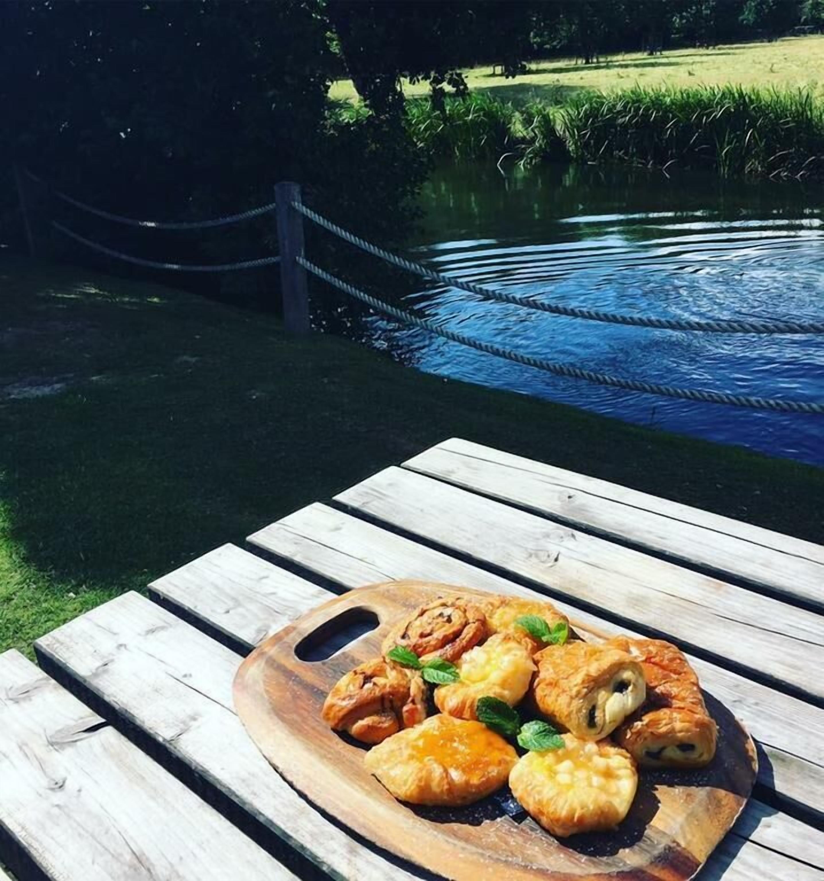 Uma mesa de madeira com um prato de doces à beira da água.