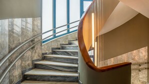 Uma escadaria de mármore com corrimão de madeira e um patamar curvo.