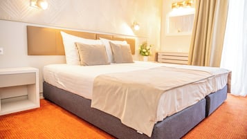 Quarto de hotel moderno com uma cama grande, uma mesa de cabeceira e uma luminária fixada na parede.