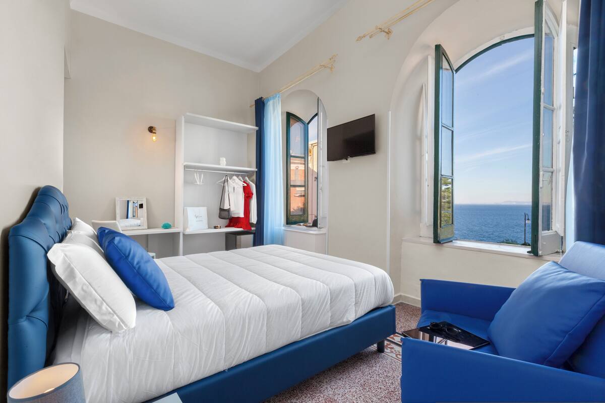 Quarto com cama, escrivaninha, cadeira e televisão.