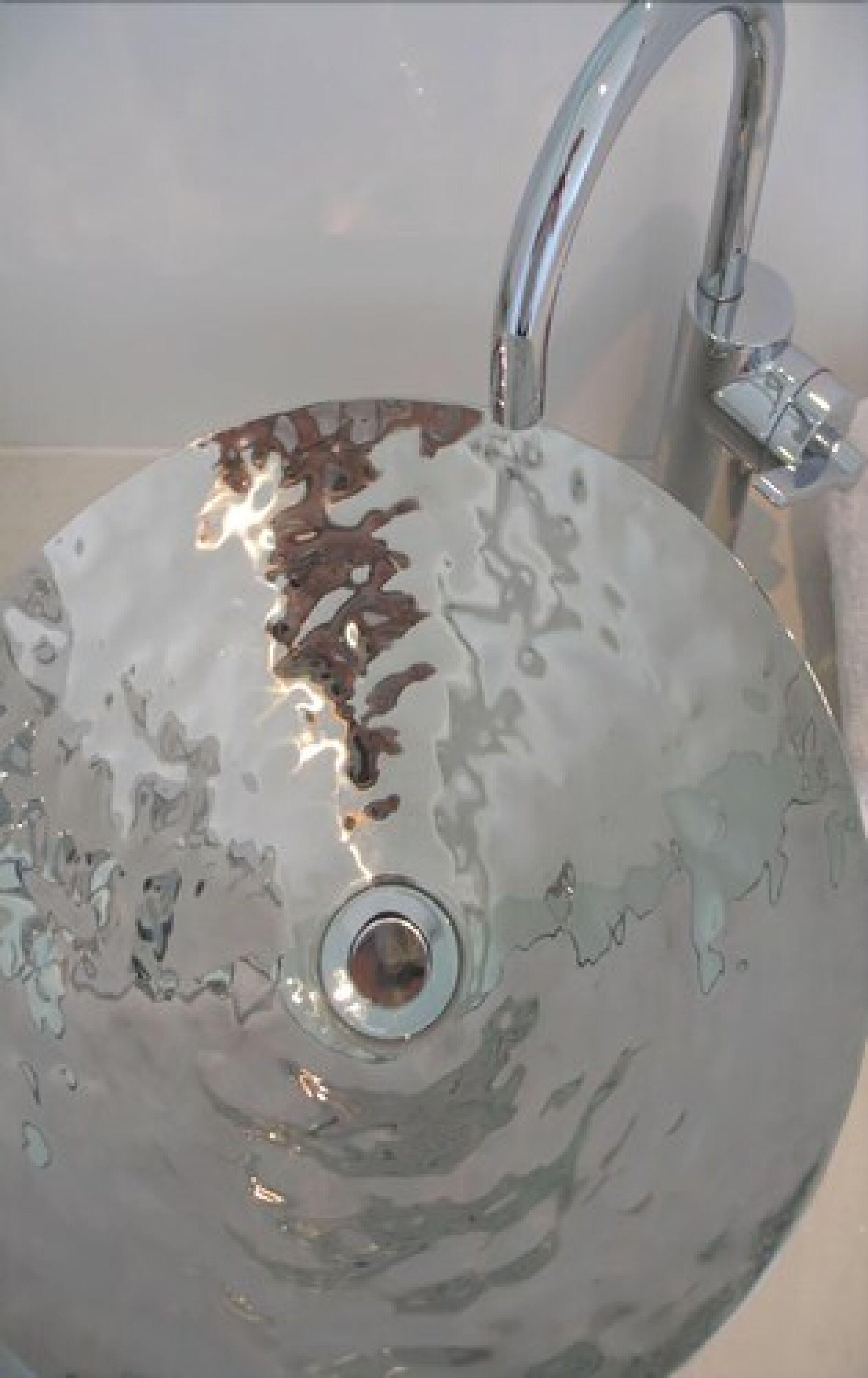 Uma pia metálica com superfície refletora e uma torneira.