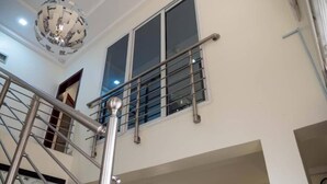 Interior com vários níveis, escada, grades de metal e luminária no teto.