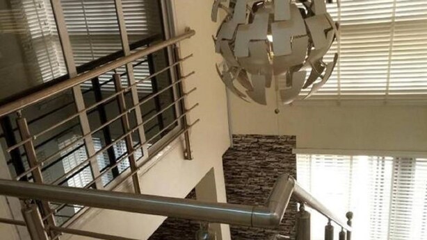 Uma escadaria com guarda-corpos de metal, um painel de parede em pedra e um globo decorativo grande.