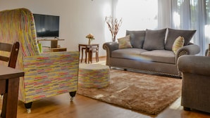 Uma sala de estar moderna com um sofá, uma poltrona e uma televisão.
