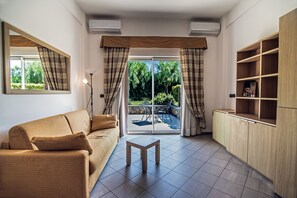 Sala de estar com sofá, mesa pequena, armário e vista para um pátio externo.