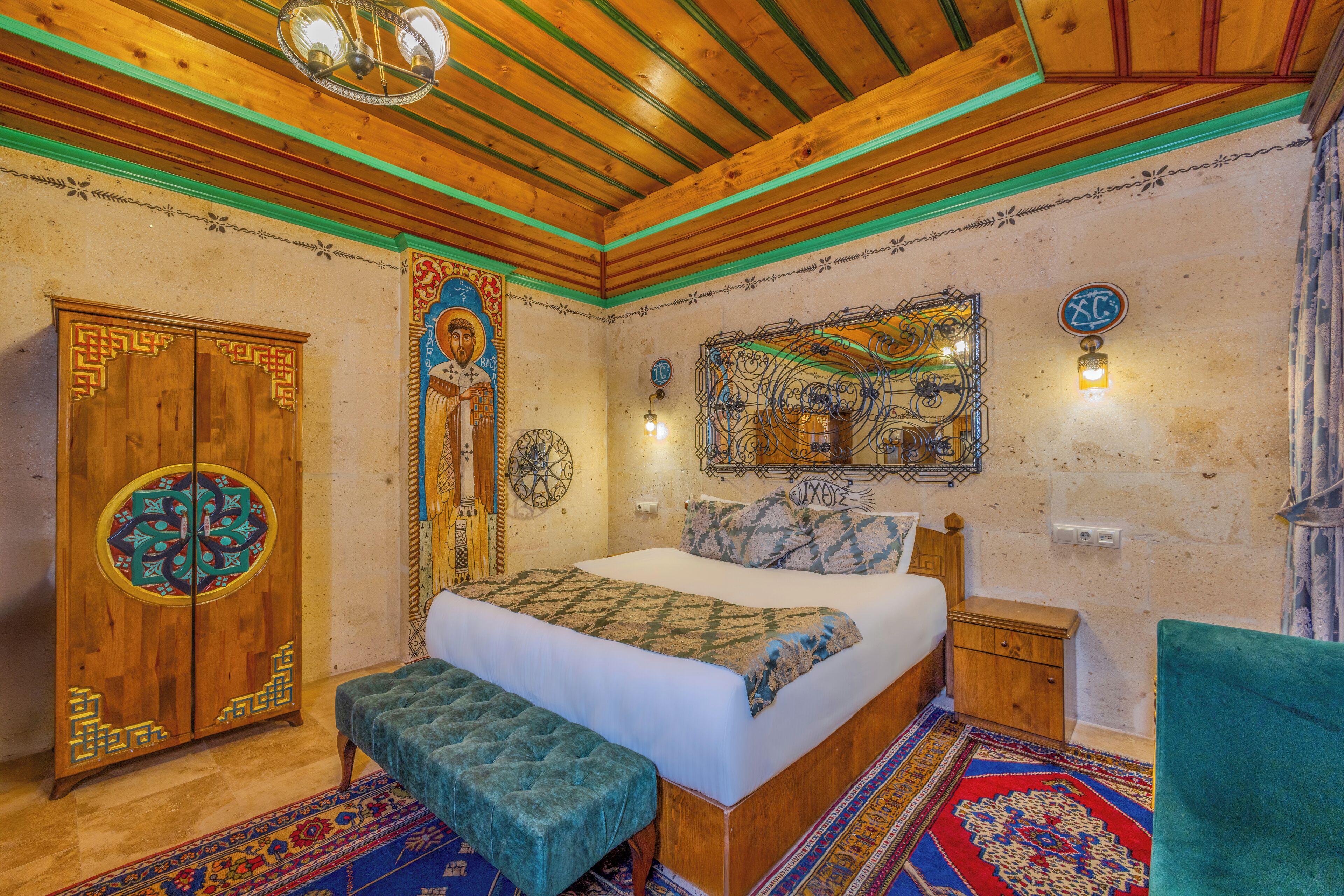 Quarto tradicional com cama de madeira, um banco, guarda-roupa e parede decorativa.