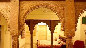 Quarto com uma cama, uma cadeira vermelha e um arco decorativo.