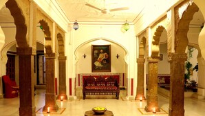 Um hall imponente com arcos decorados, um banco central e um quadro na parede.