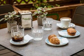 Uma mesa com um croissant, um muffin, uma xícara de café e dois copos de água.