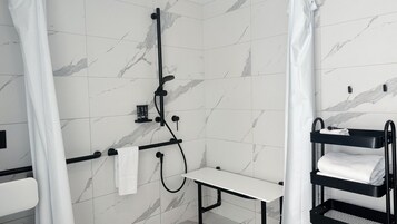 Uma casa de banho moderna com chuveiro, porta-toalhas e uma estante preta.