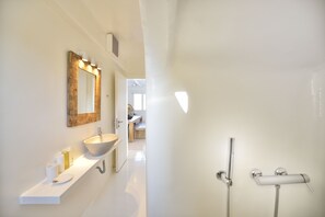 Uma casa de banho moderna com um espelho grande, uma sanita branca e uma área de duche.