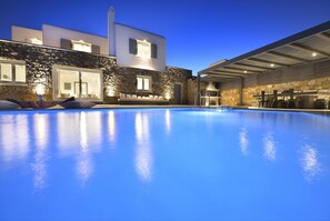 Um edifício moderno com piscina, paredes de pedra e área de estar ao ar livre.