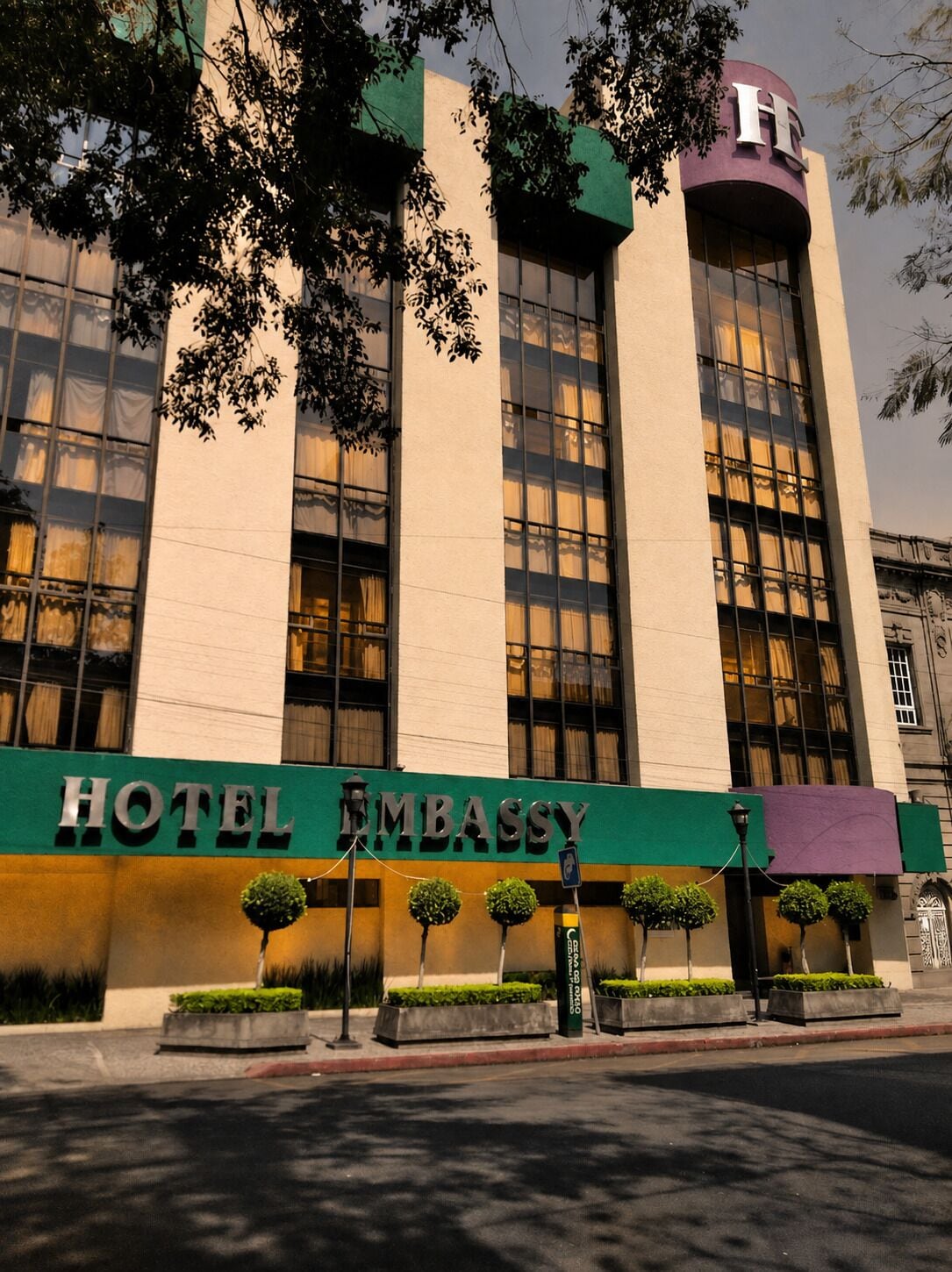Um edifício com uma placa indicando 'HOTEL EMBASSY' e um 'H' grande no topo.