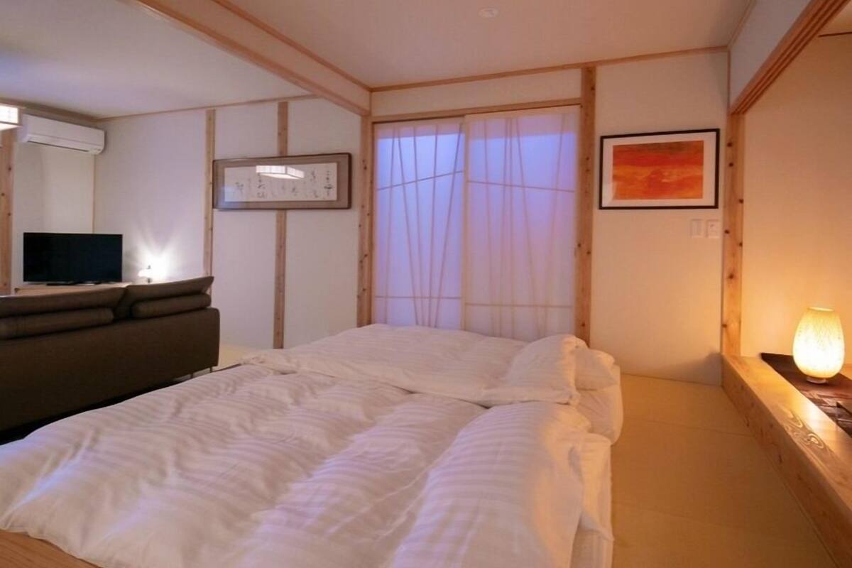 Quarto com cama, televisão, moldura e abajur.