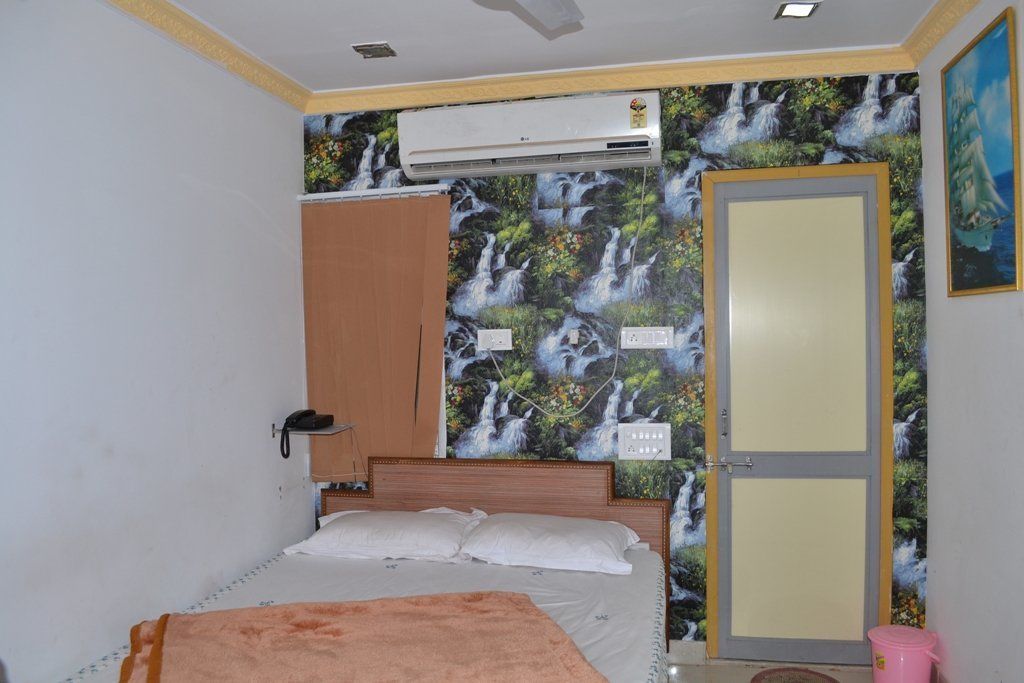 Quarto com cama, ar condicionado, porta e parede com papel de parede com tema natureza.