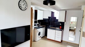 Cozinha moderna com máquina de lavar, bancada preta e um relógio na parede.