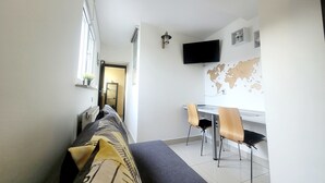 Um espaço compacto com sofá, mesa de jantar com cadeiras, TV de tela plana na parede e um mapa-múndi.