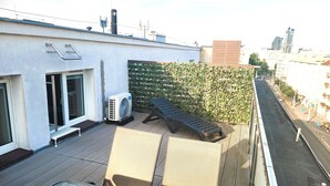 Terraço no telhado com piscina, cadeiras de descanso, ar condicionado e vista para a cidade.