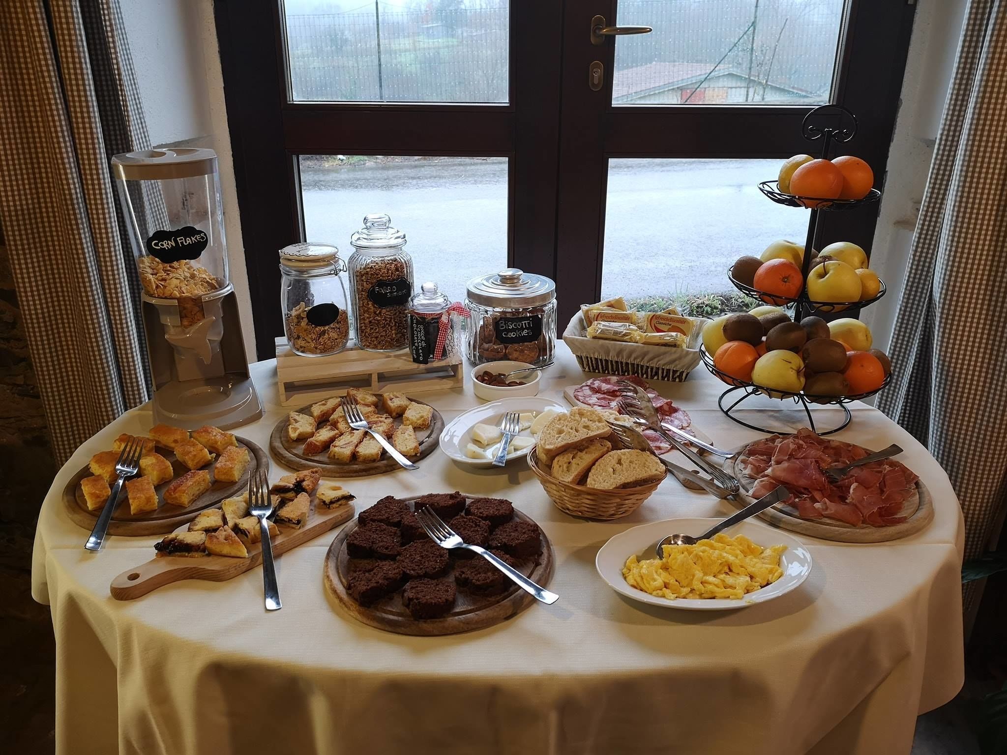 Um buffet de café da manhã com diversos alimentos e utensílios sobre uma mesa.