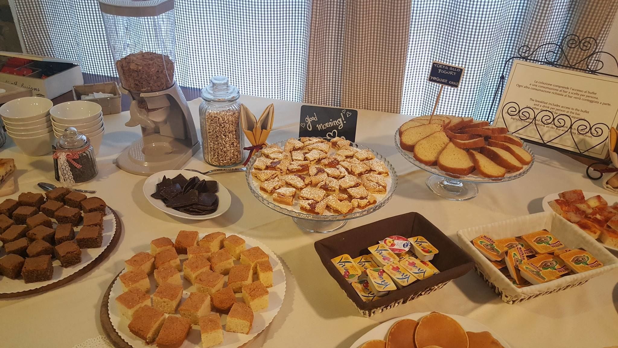 Uma mesa de buffet com diversos alimentos, incluindo bolos, brownies e doces.